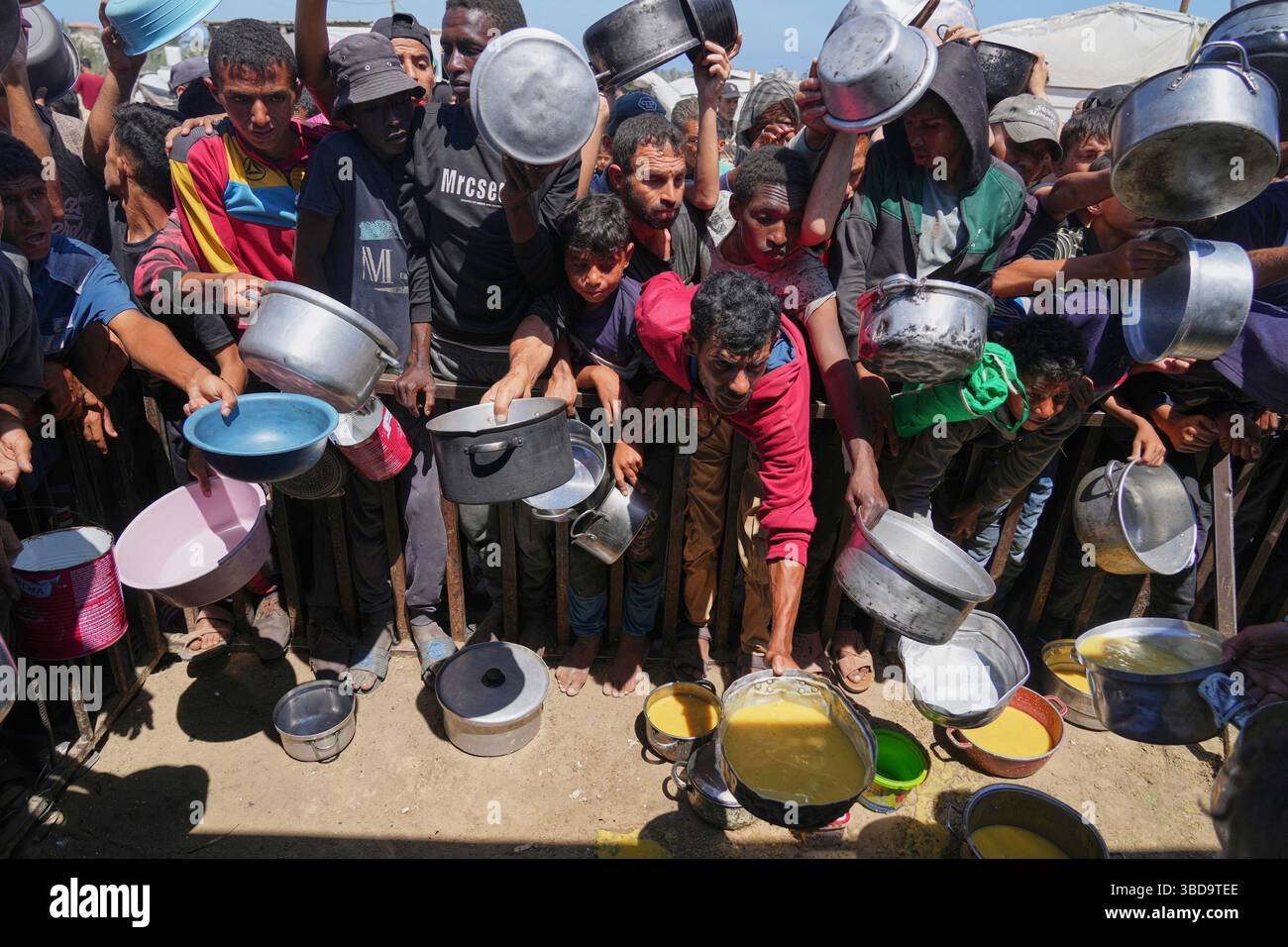 Palestinians struggle to receive cooked food distributed at a community ...