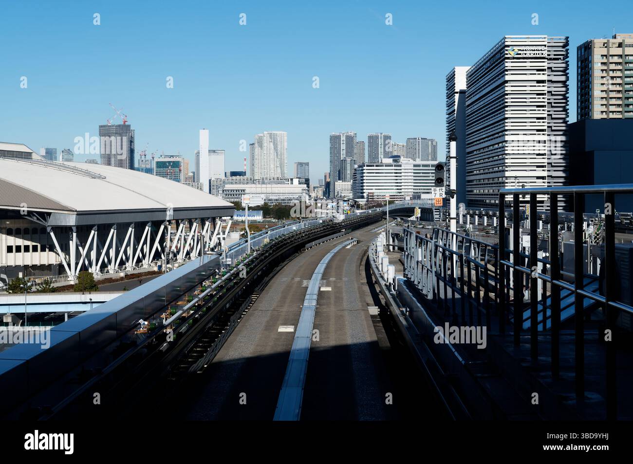 Tokyo’s skyline looms ahead as the Yurikamome Line curves past the Ariake Coliseum Stock Photo ...