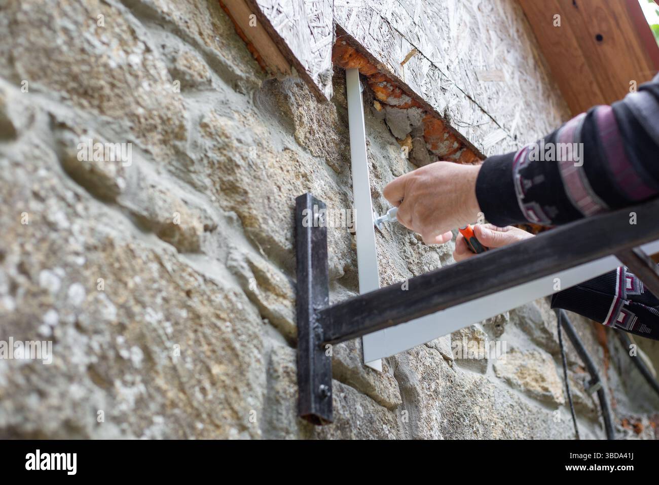 A man fixes a metal bracket for installing an air conditioner with a ...