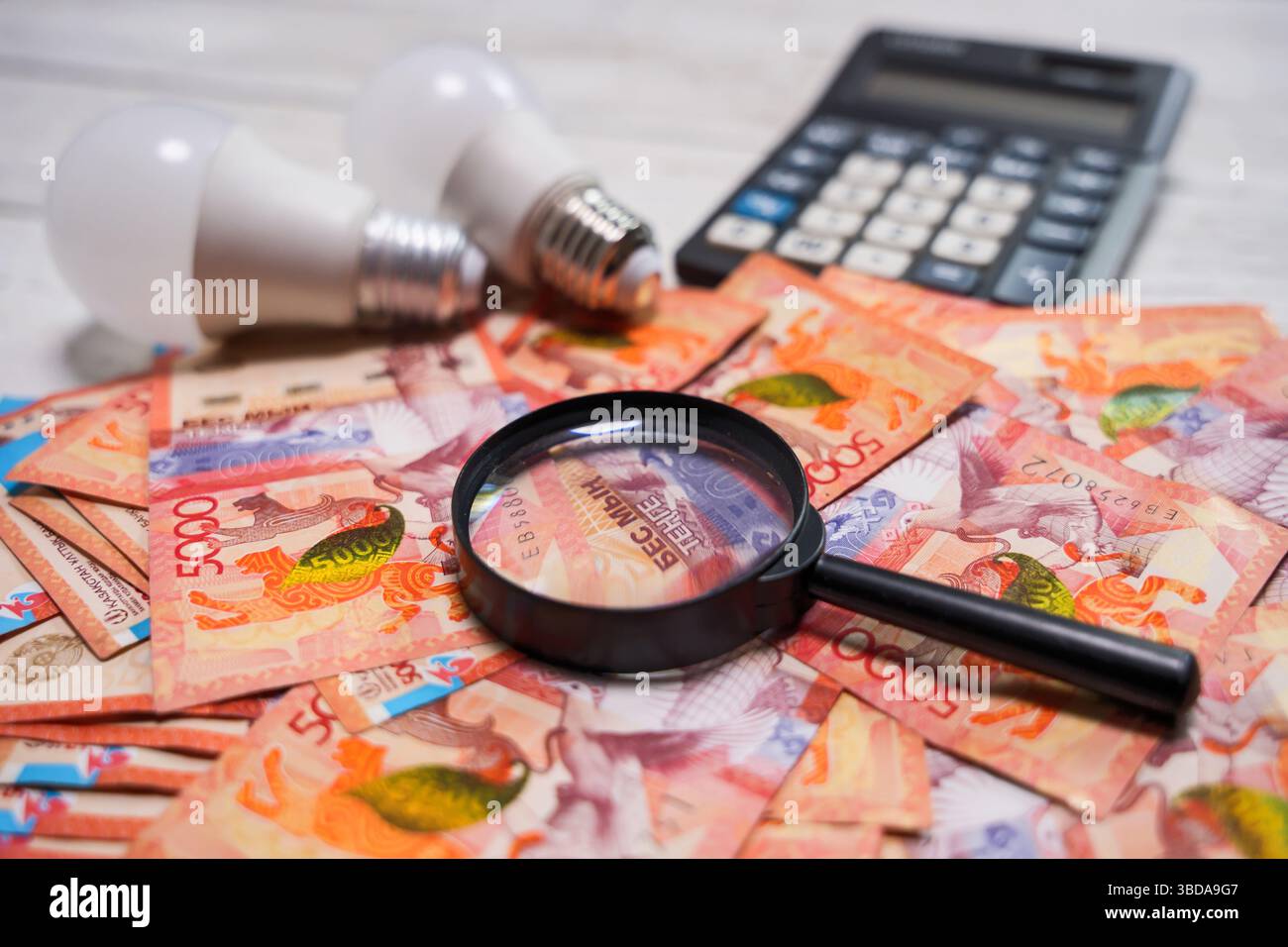 Magnifying glass on tenge banknotes with LED lamps and calculator ...