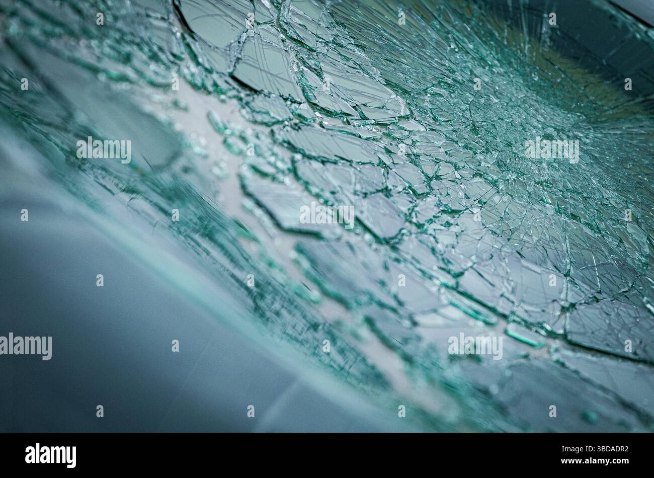 Fractured windshield with radiating cracks. Close-up of spiderweb cracks in a damaged safety ...