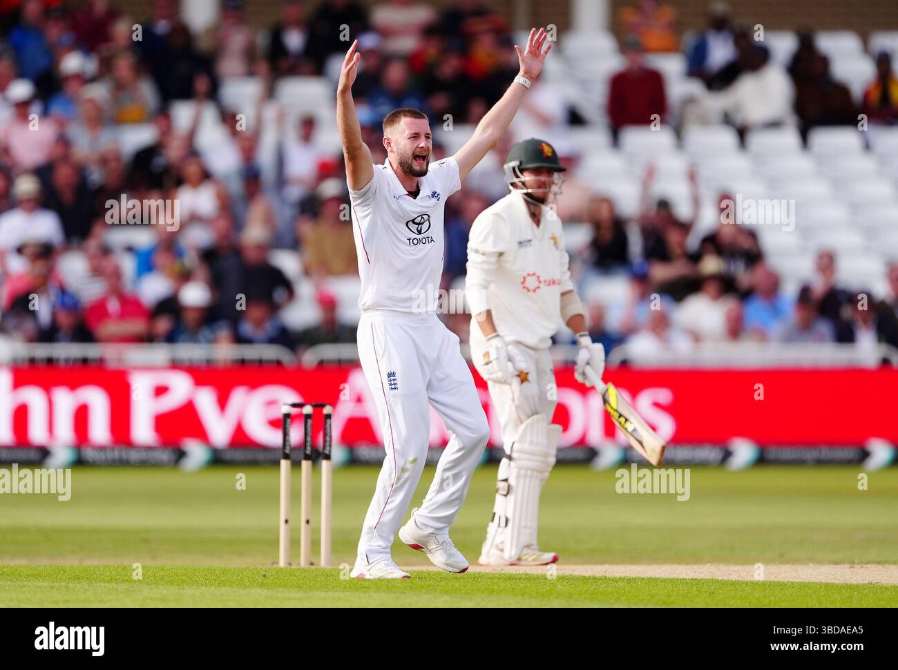 England's Gus Atkinson (left) celebrates tacking the wicket of Zimbabwe ...