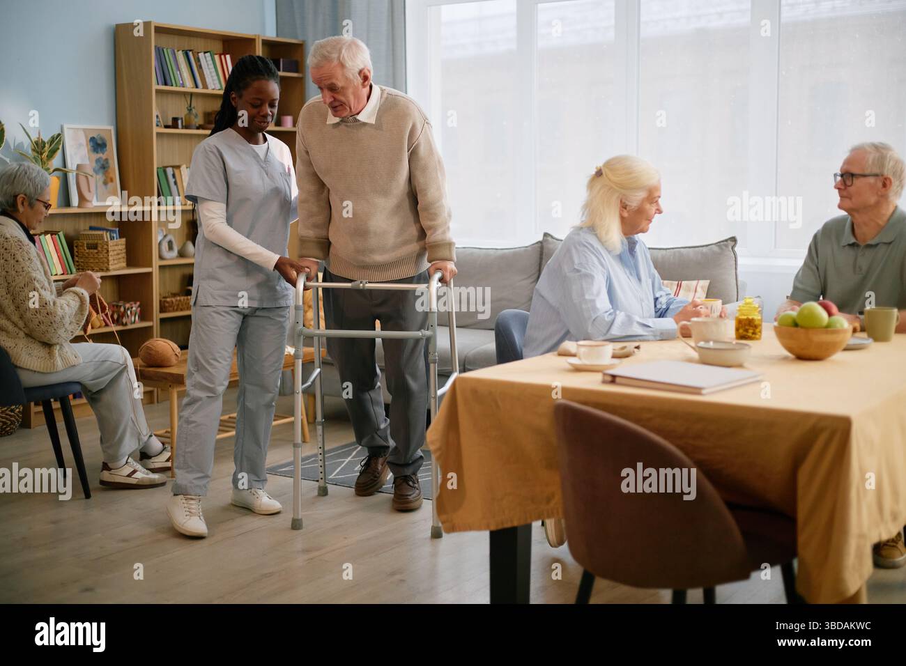 Elderly Man Using Walker Assisted by Caregiver in Facility Stock Photo ...