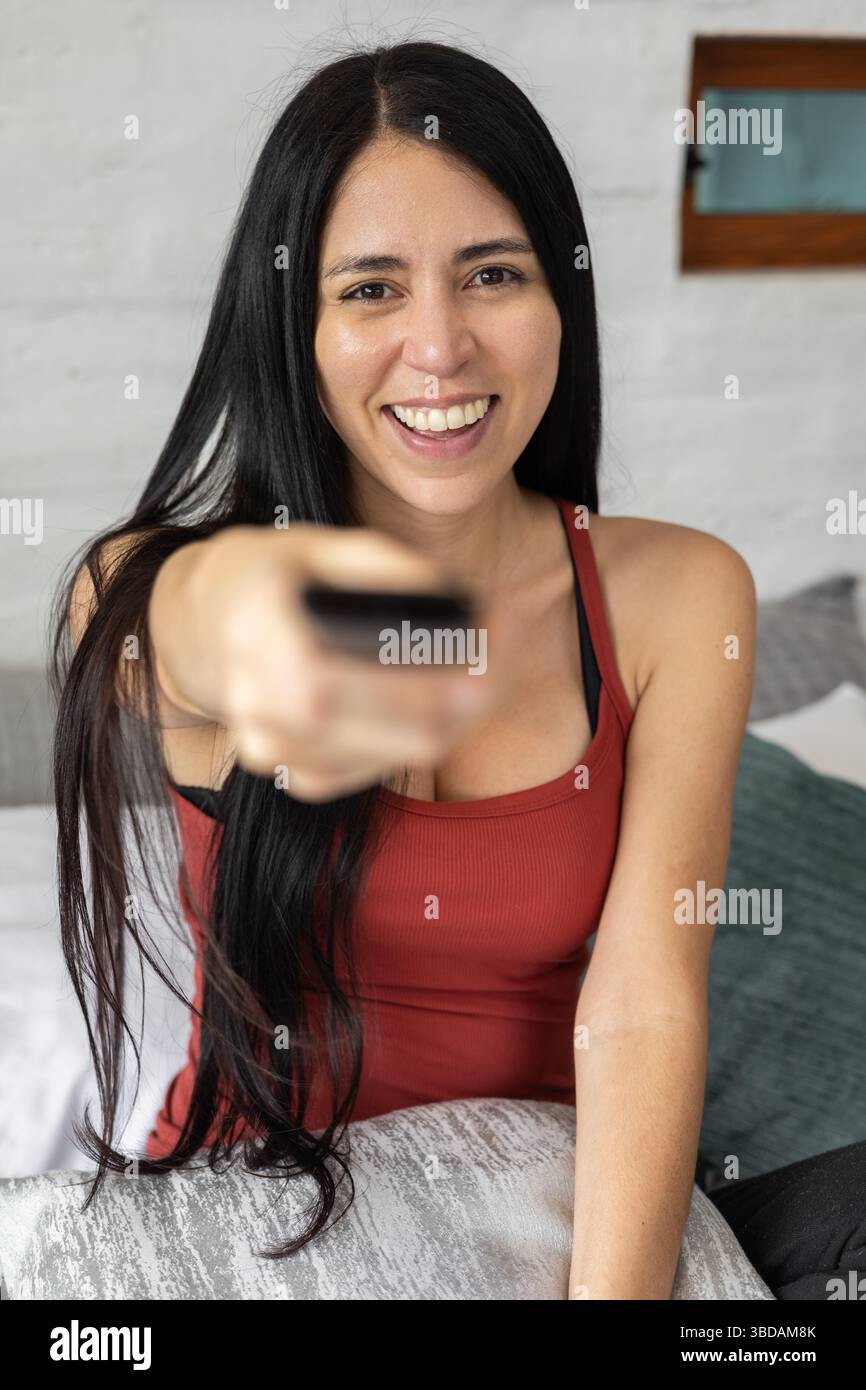 From the TV’s view, she smiles on the bed, aiming the remote with joy and ease, ready to dive ...