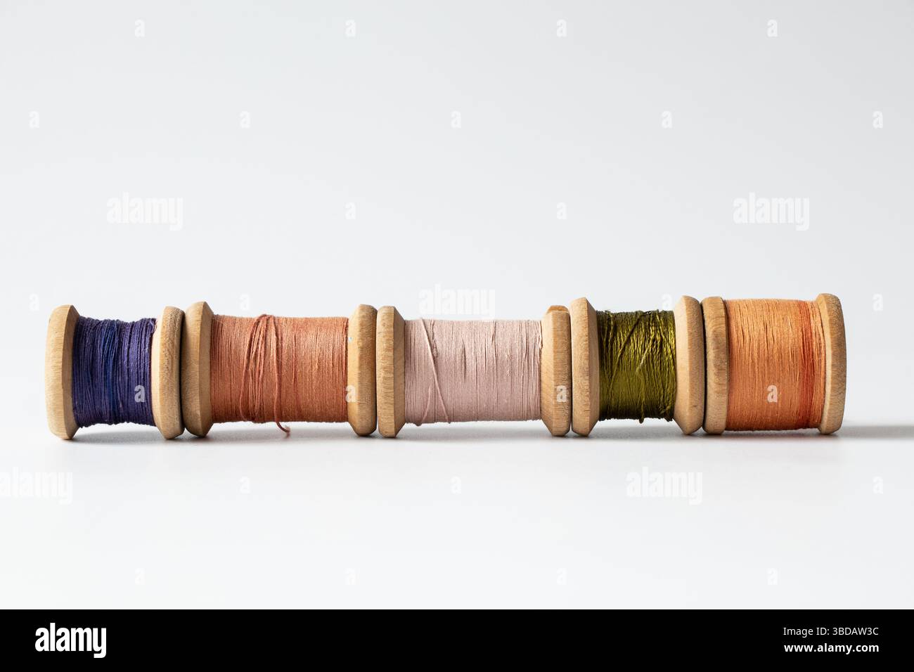 Wooden spools of threads of different colors on white background ...