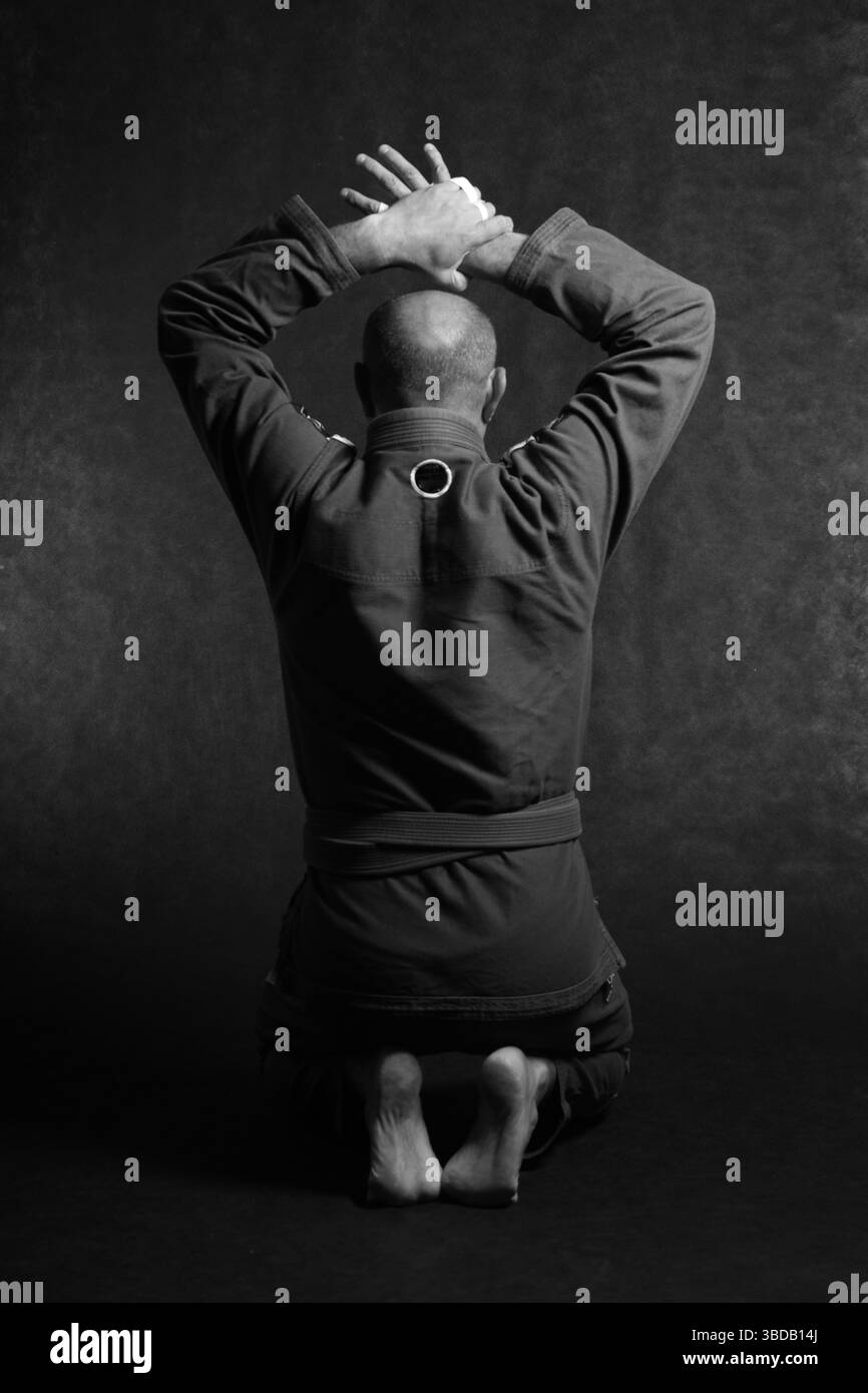 A person is kneeling on the ground, viewed from behind, wearing a ...