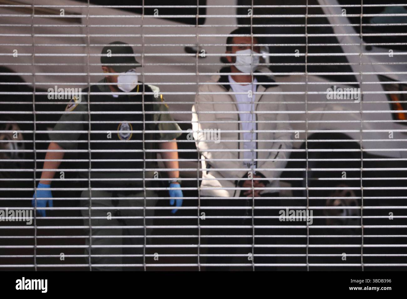 A person is handcuffed and escorted into a DHS van inside the Edward R ...