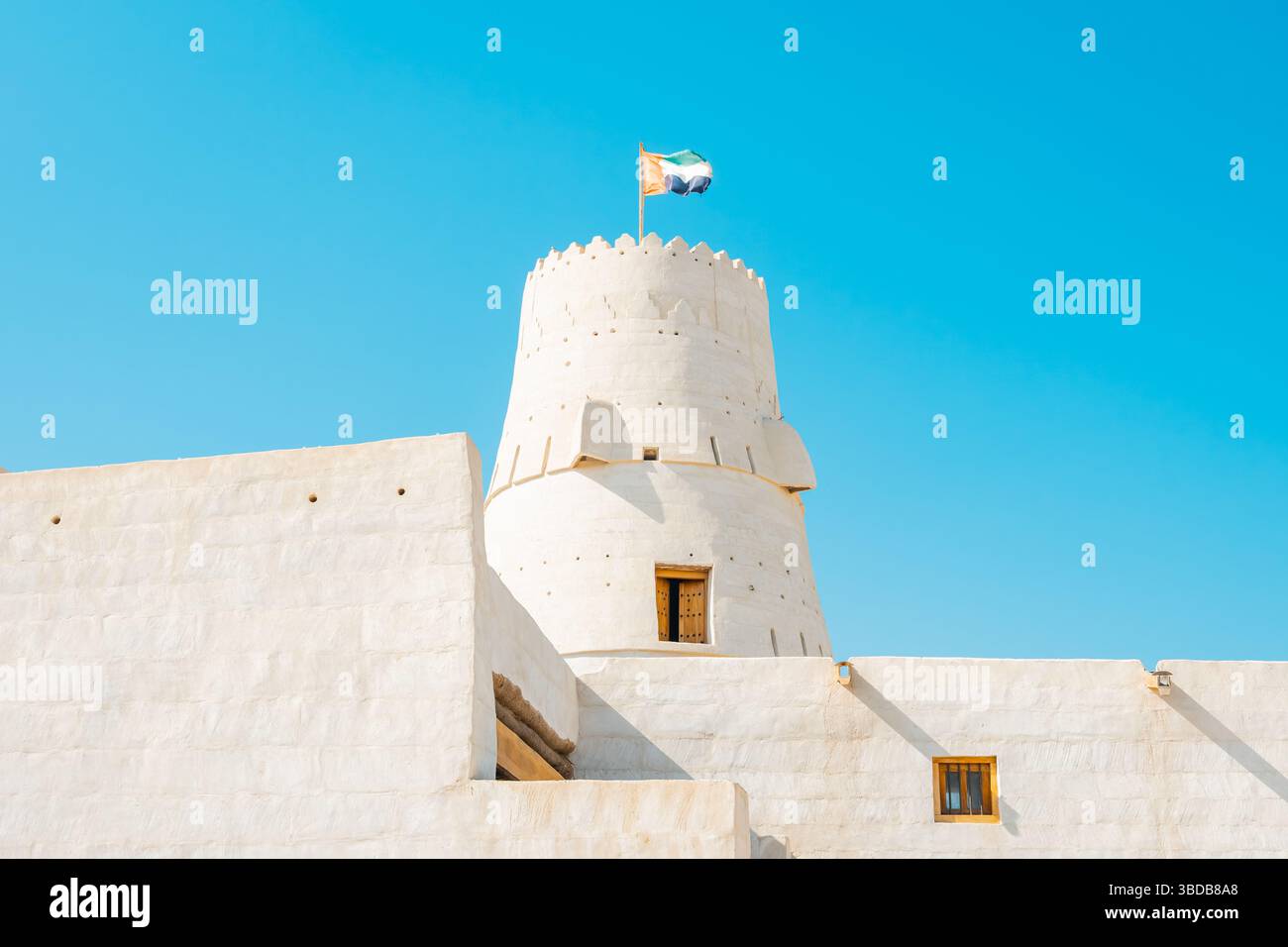 Stone arabic watchtower with waving United Arab Emirates National Flag ...