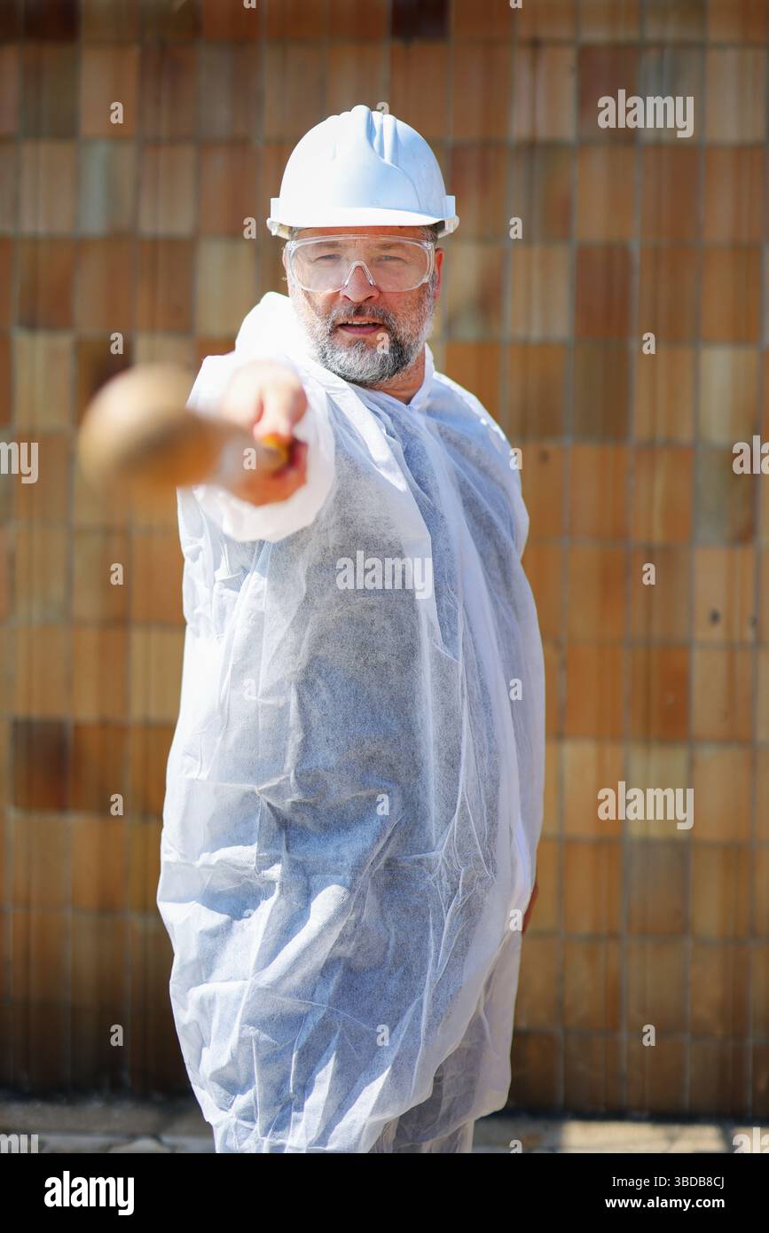Mature male in protective suit and helmet prepares to smash. Rage room ...