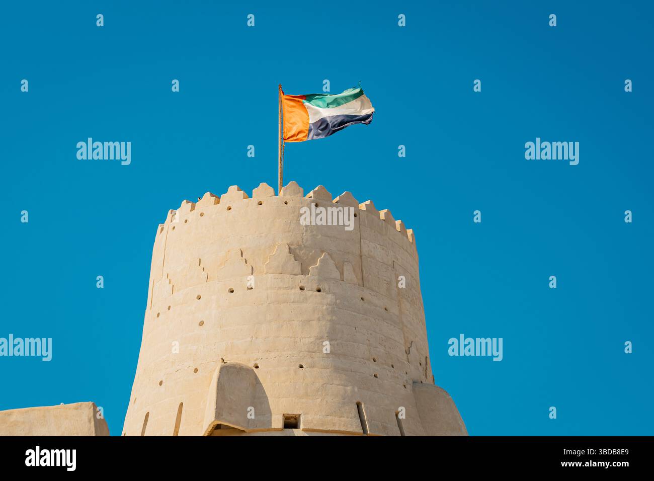 Stone arabic watchtower with waving United Arab Emirates National Flag ...