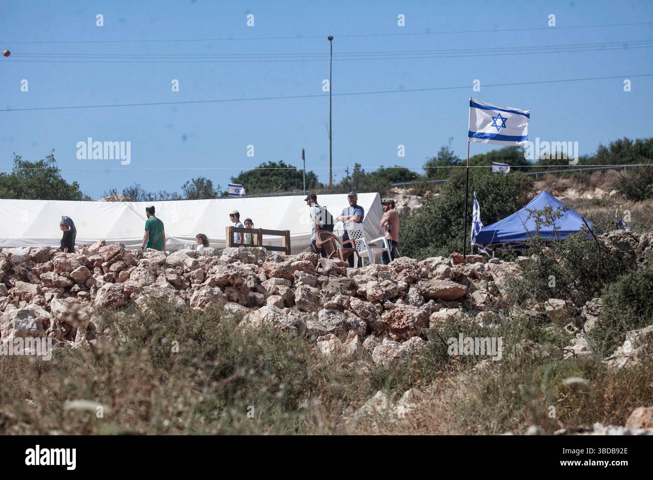 Jewish settlers walk past a tent set up by settlers on Palestinian land ...