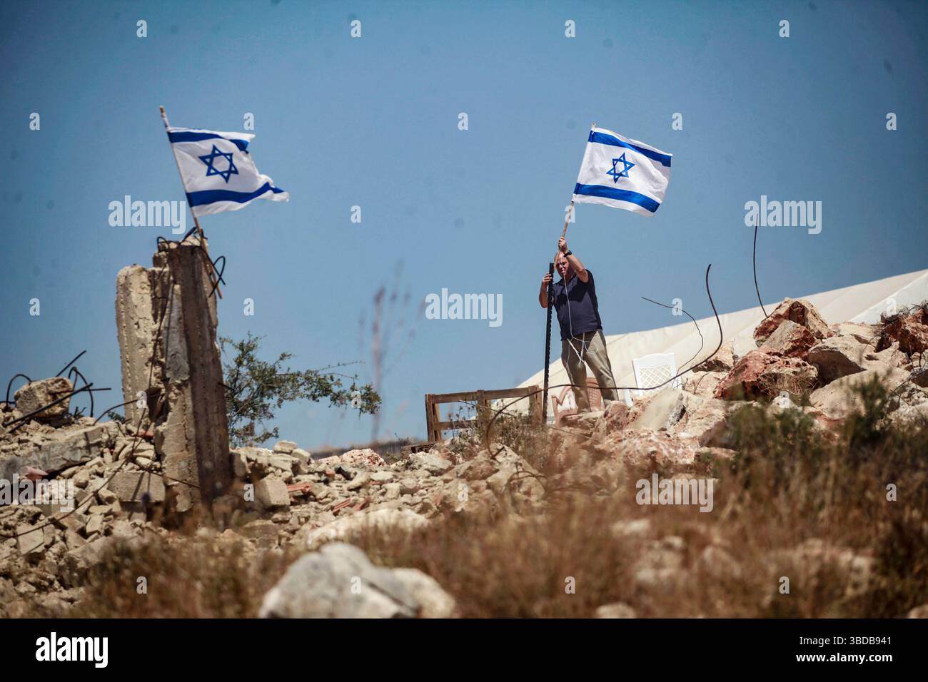 A Jewish settler raises an Israeli flag on Palestinian land near ...