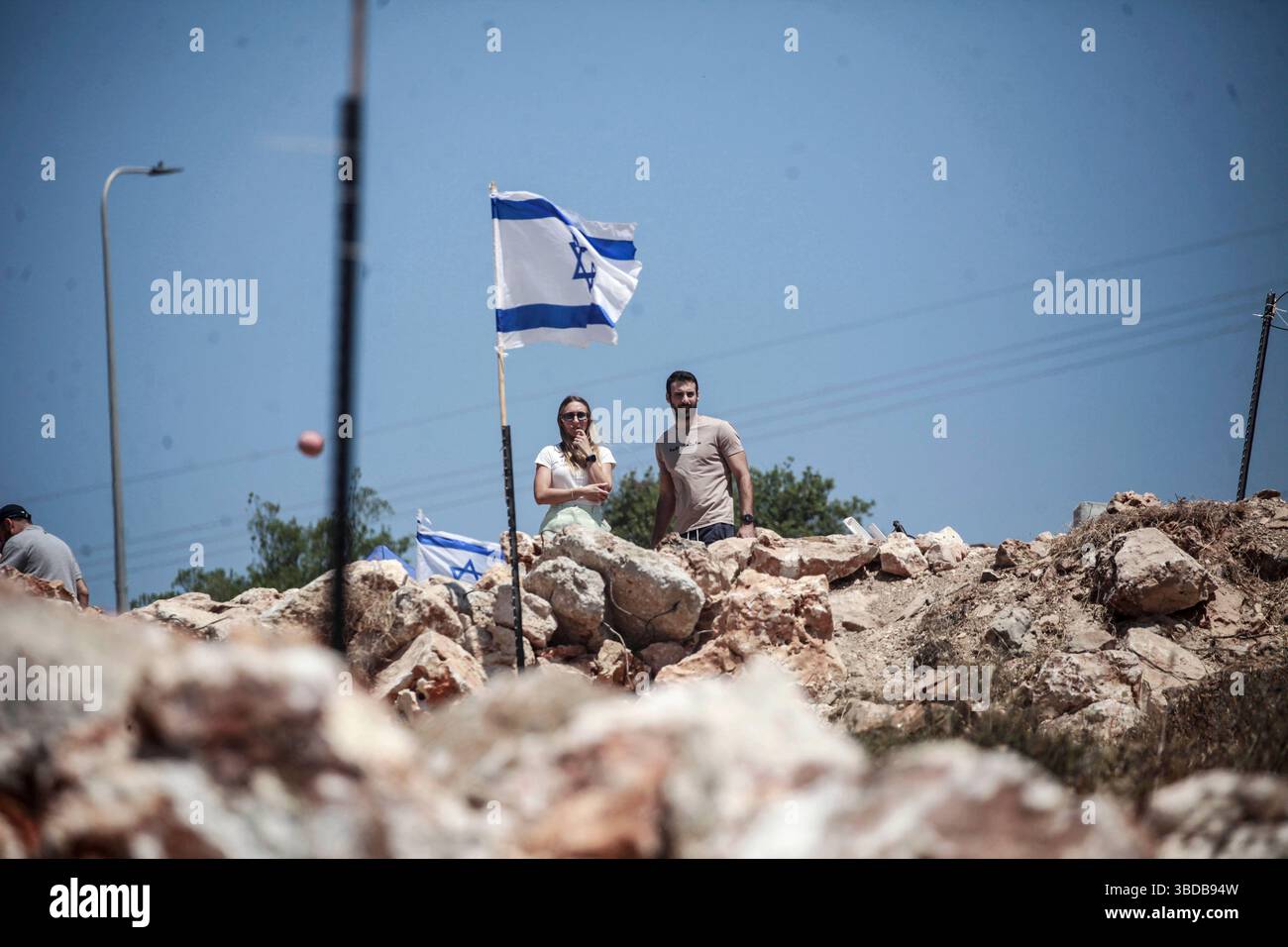 A Jewish settler raises an Israeli flag on Palestinian land near ...