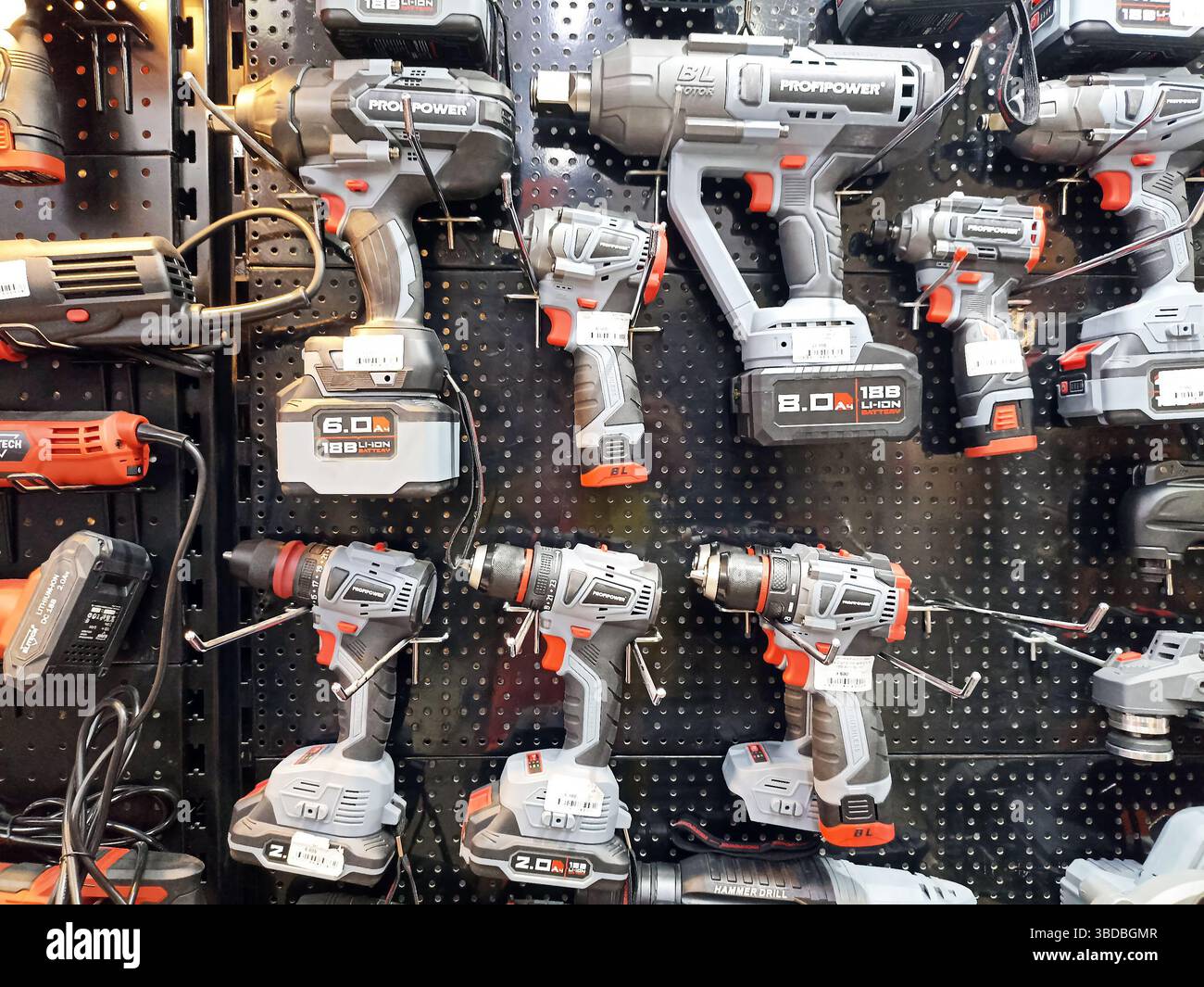Display of various cordless power drills and impact drivers on pegboard ...