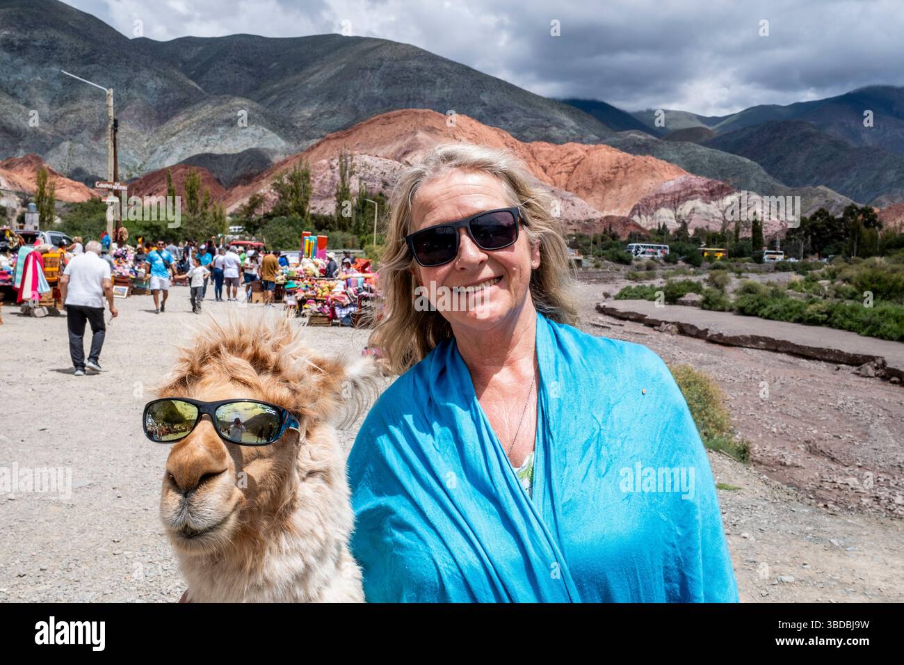 A Tourist Poses With A Llama, Both Are Wearing Sunglasses With The Hill ...