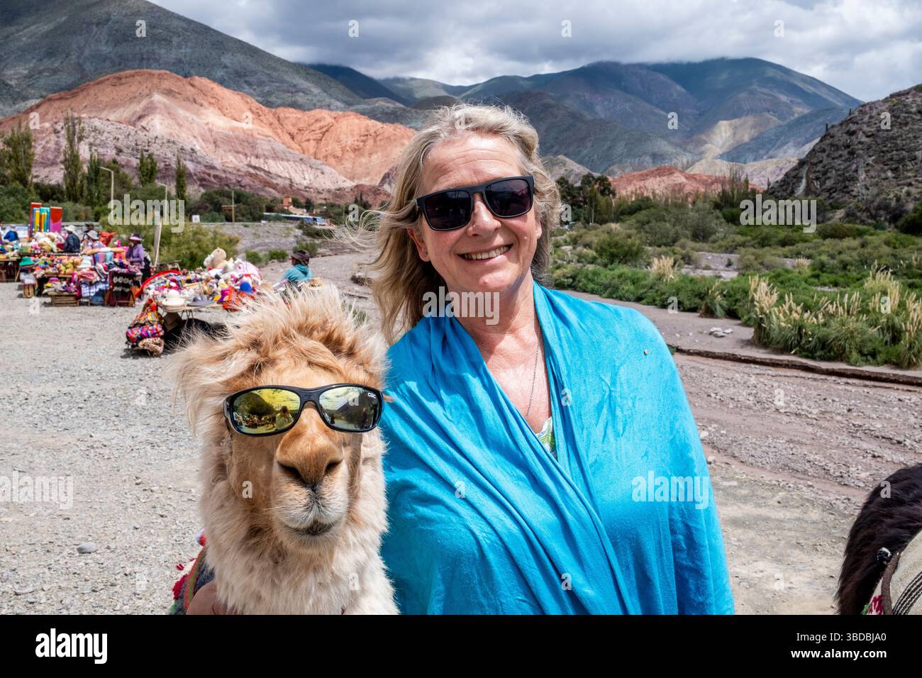 A Tourist Poses With A Llama, Both Are Wearing Sunglasses With The Hill ...