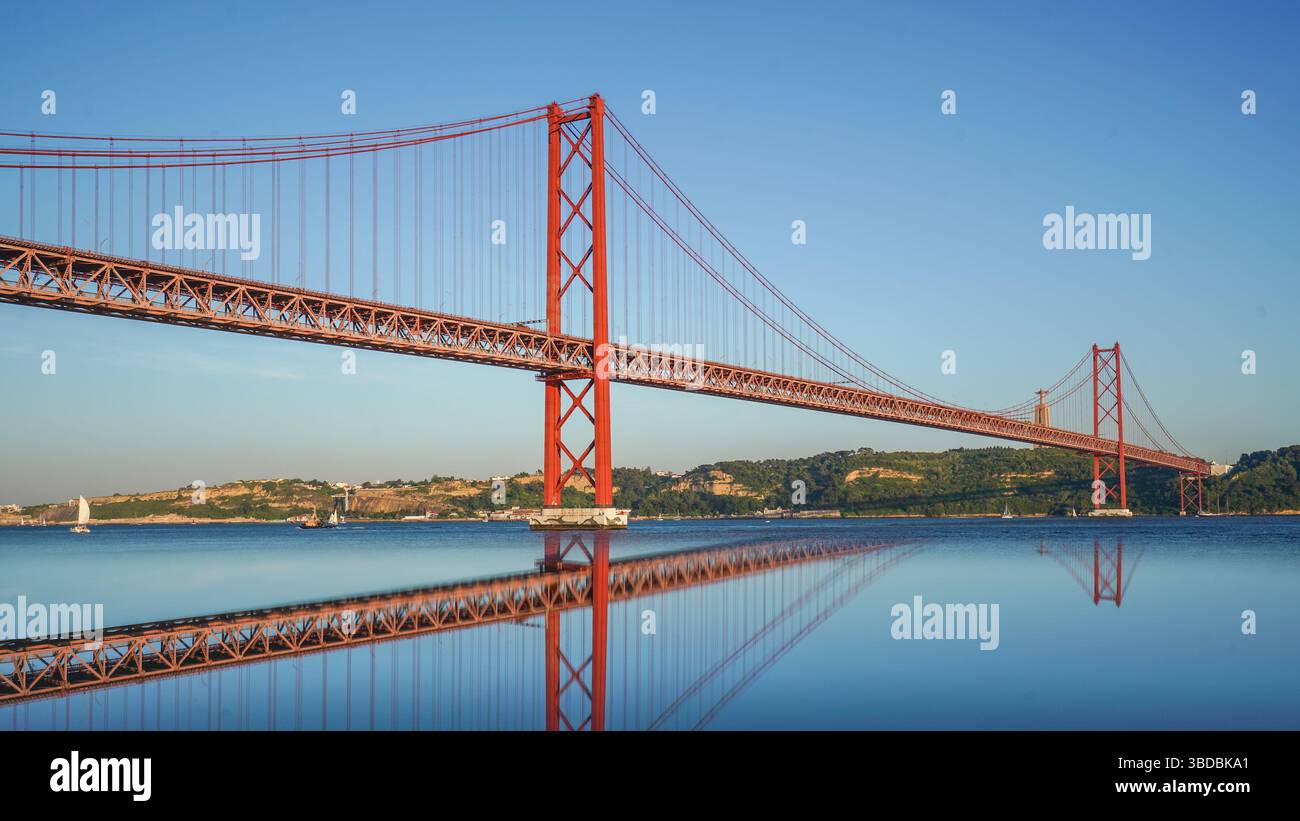 Lisbon, Portuagl, May 23rd 2025: A striking red suspension bridge, the ...