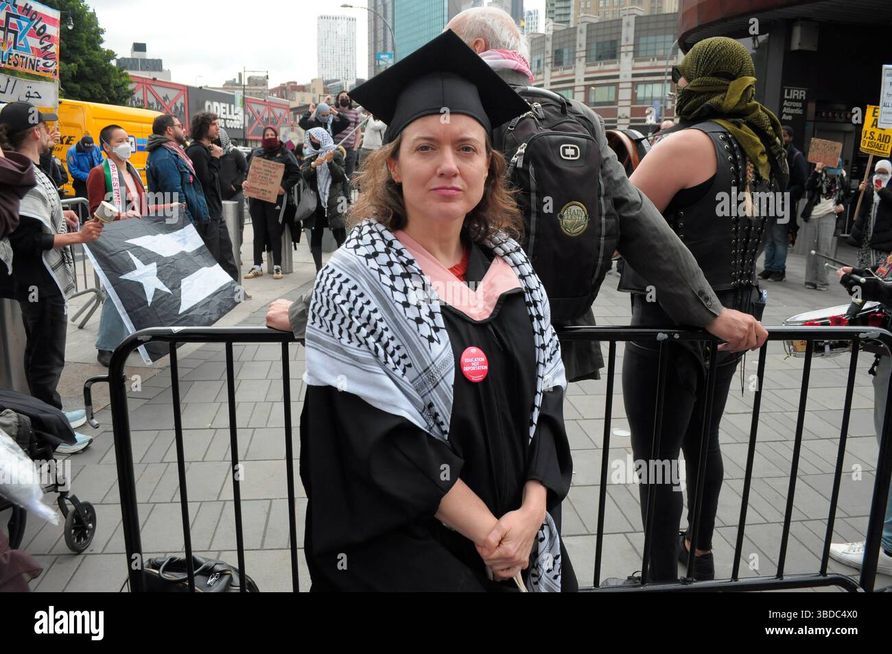 A pro-Palestine demonstrator wears a graduation cap and gown at a rally ...
