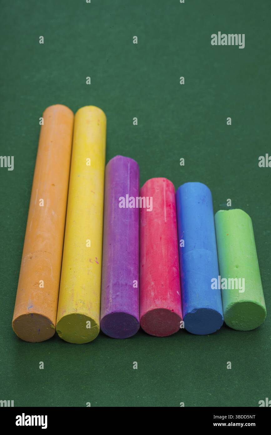 Six pieces of chalk, all of different size and bright colours lie ...