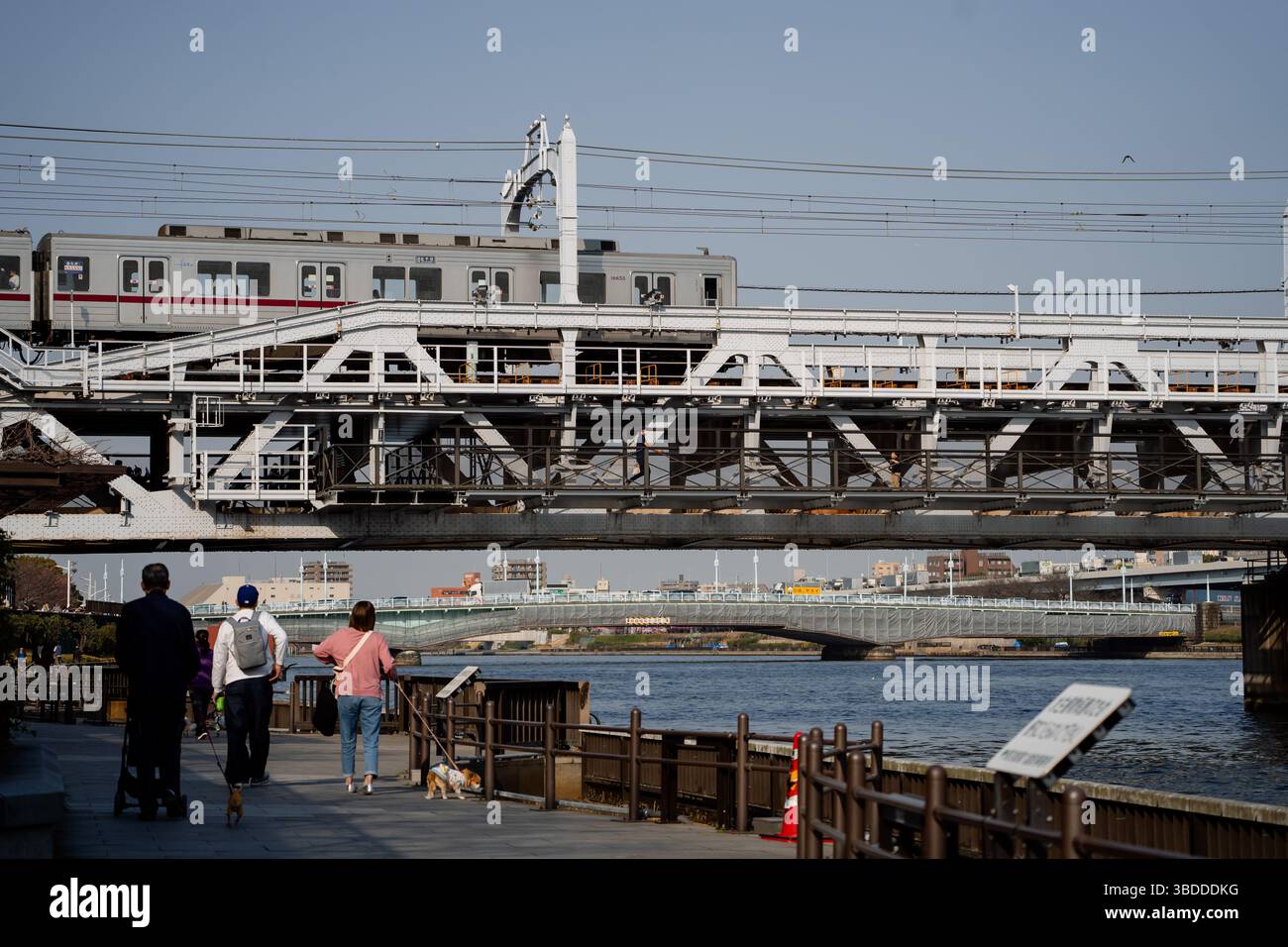 Asakusa, Tokyo, Japan 03-23-2025: Train and people crossing the river ...