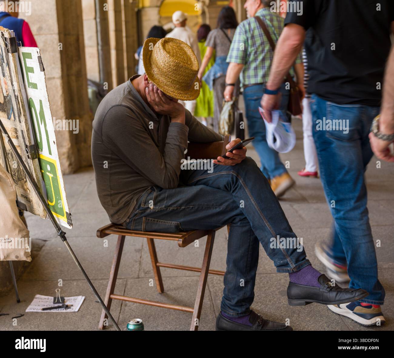Madrid, Spain. May 18th 2025.A homeless man sitting looking his mobile ...