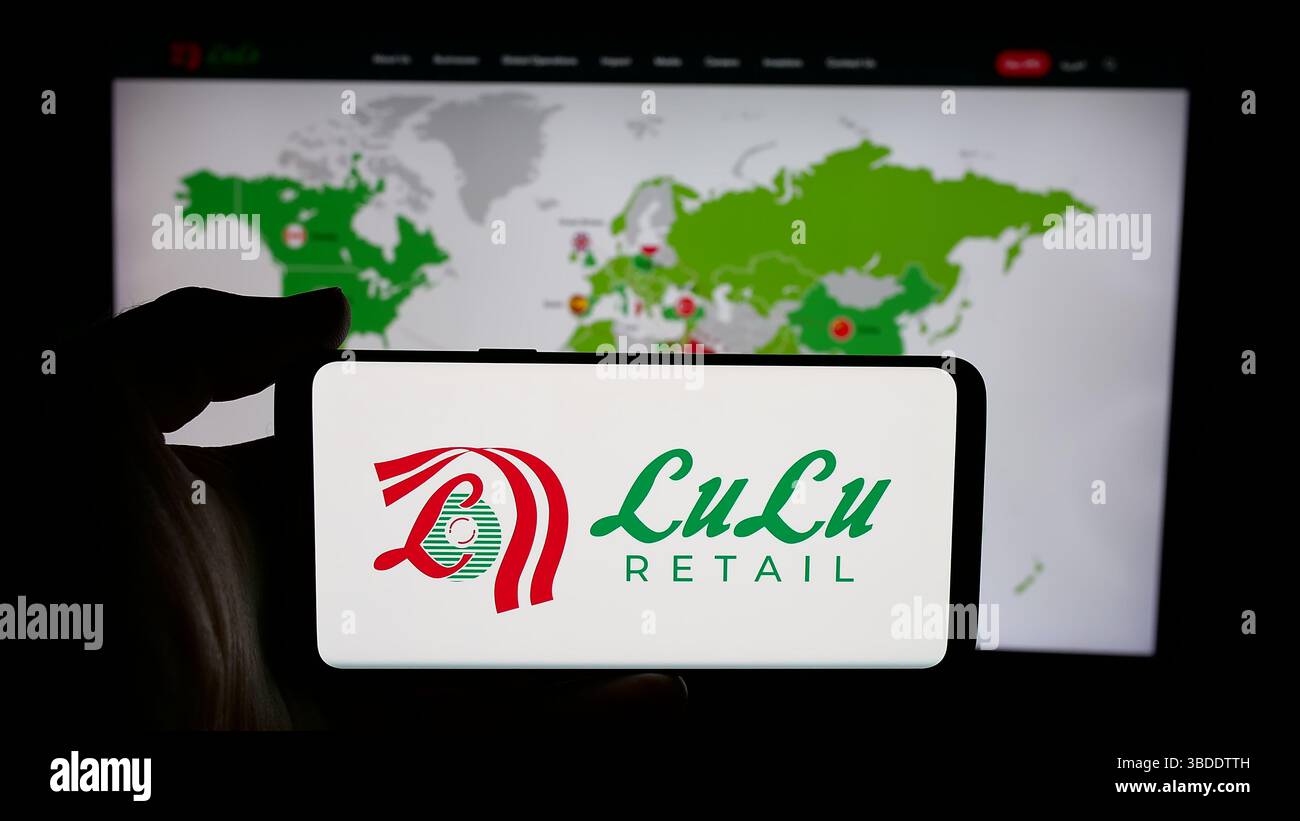 In this photo illustration, a person is holding a cellphone with the logo of company Lulu Retail ...