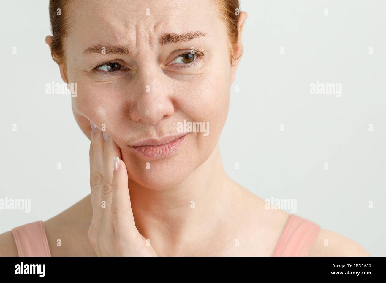 A woman suffers from severe toothache, she holds her hand to a sore ...