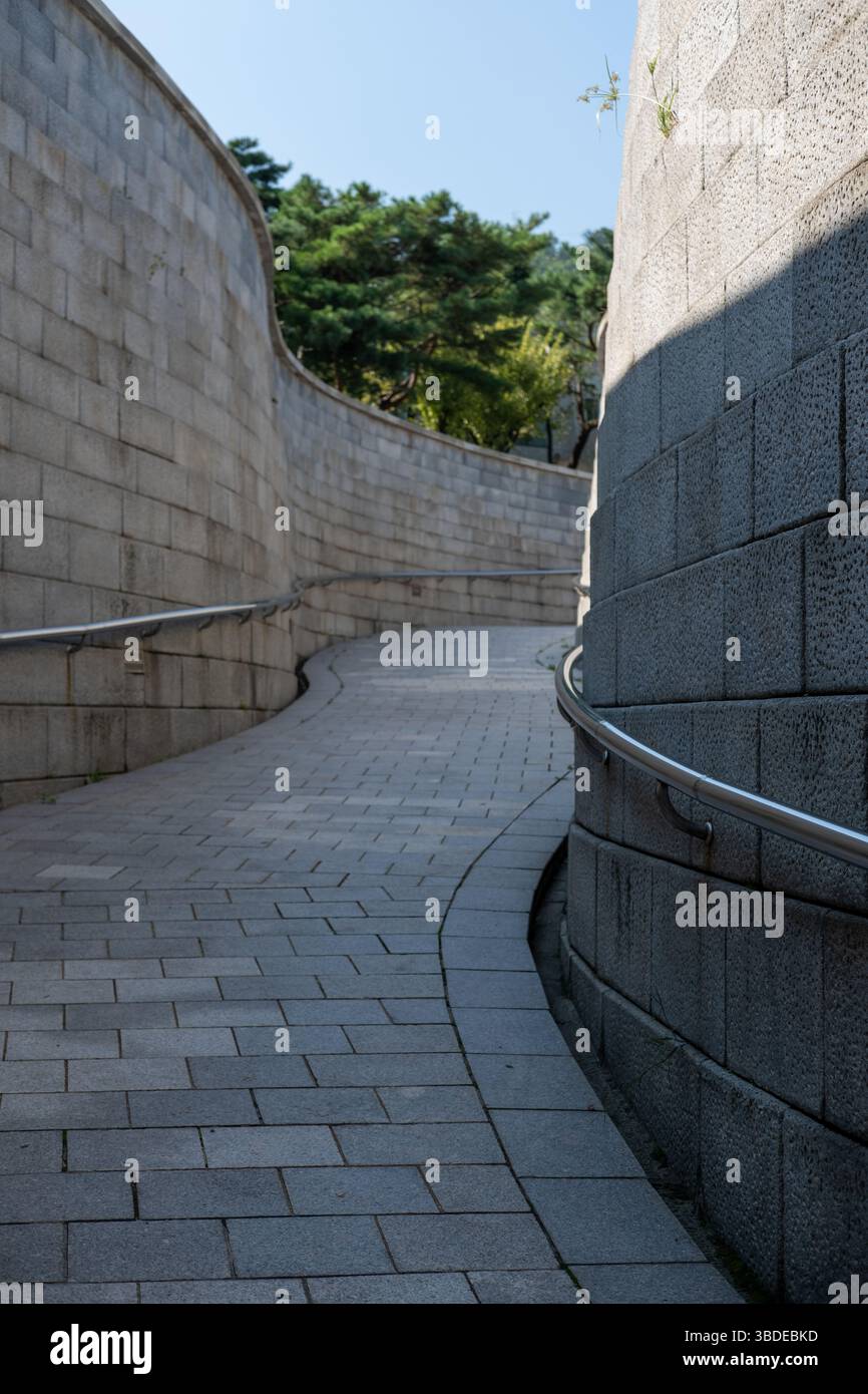 Curved stone pathway with steel handrails, leading uphill under clear ...