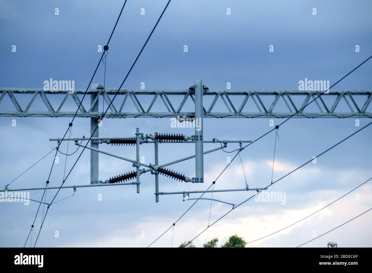 A close-up of railway power lines and overhead catenary structure ...