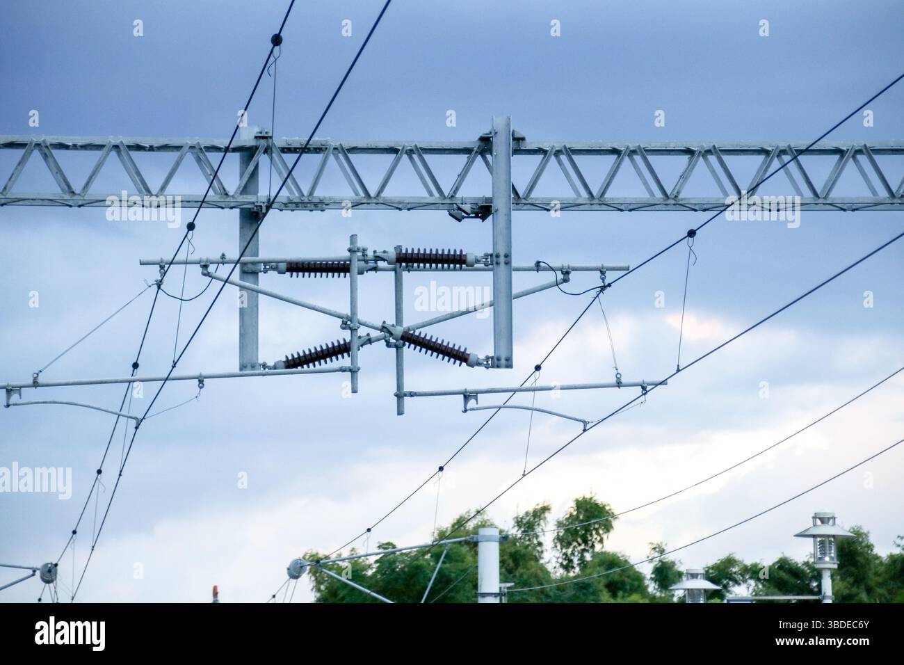 A close-up of railway power lines and overhead catenary structure ...