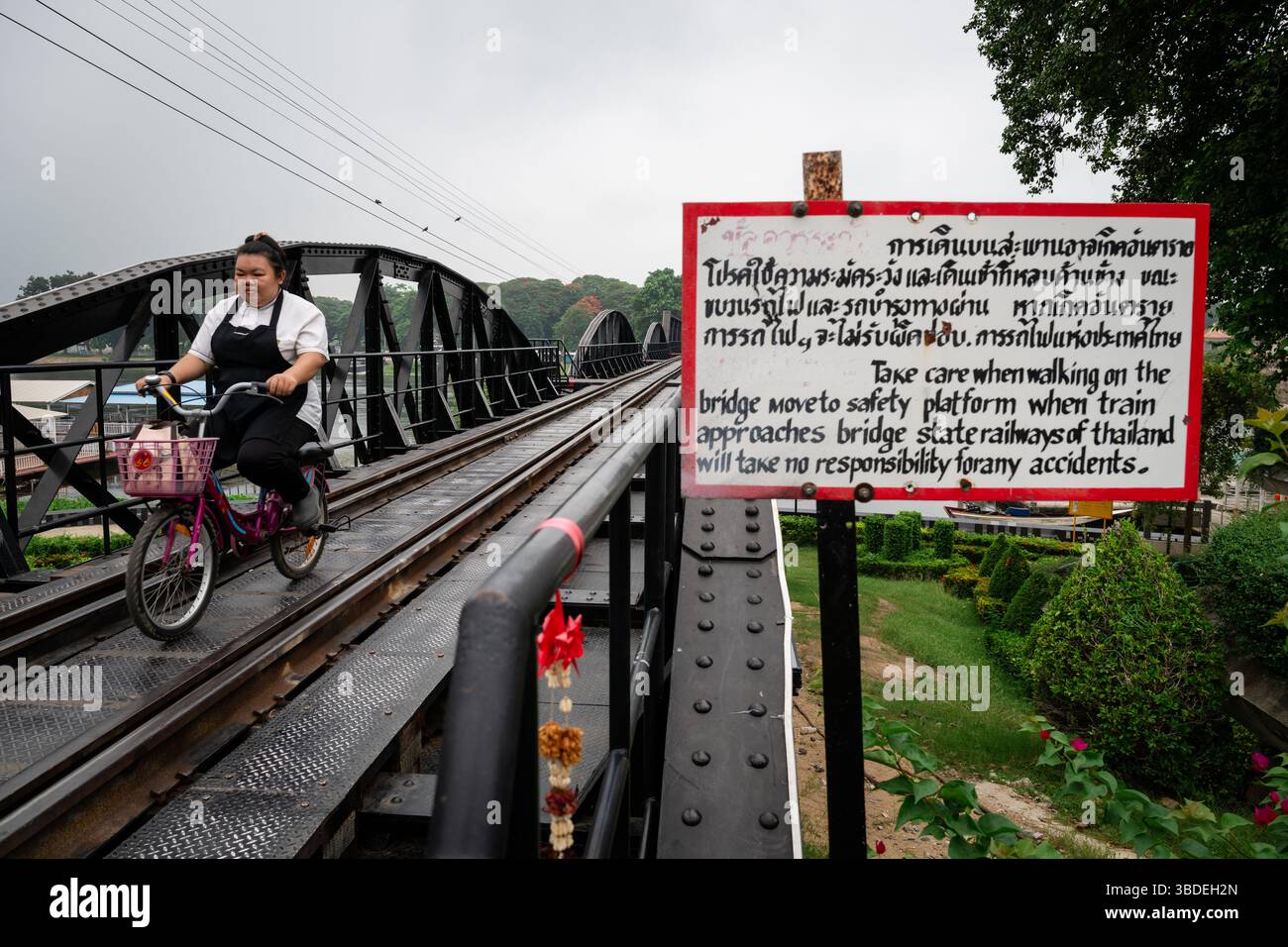 Local cyclist crosses the historic Bridge Over River Kwai alongside a ...