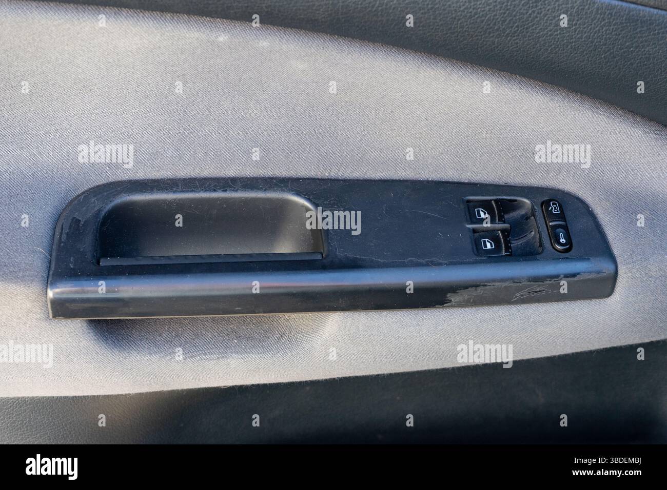 A close-up view of a car door panel showing the window control switches ...