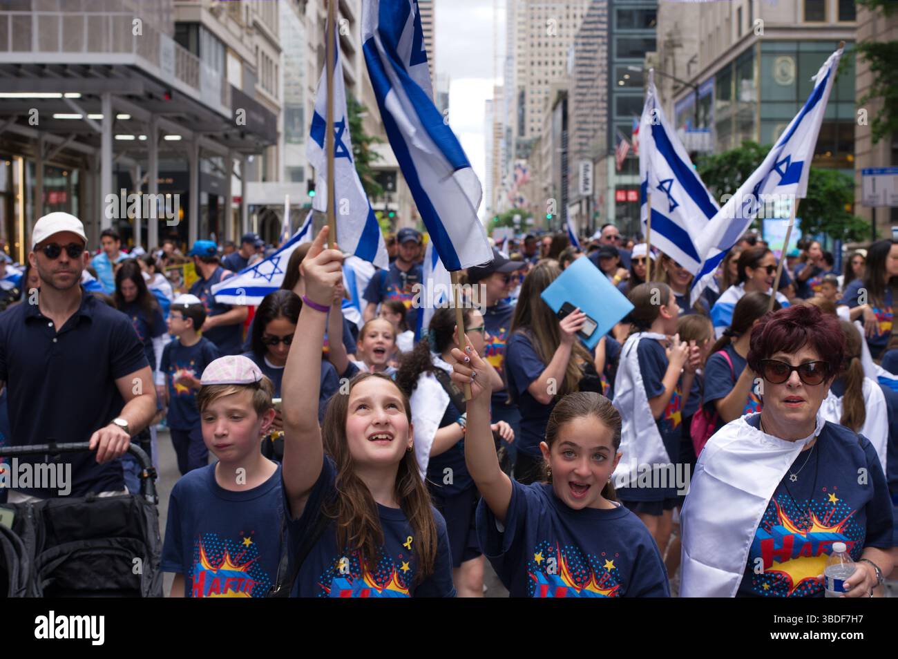 A large crowd participates in a daytime parade, many holding Israeli ...