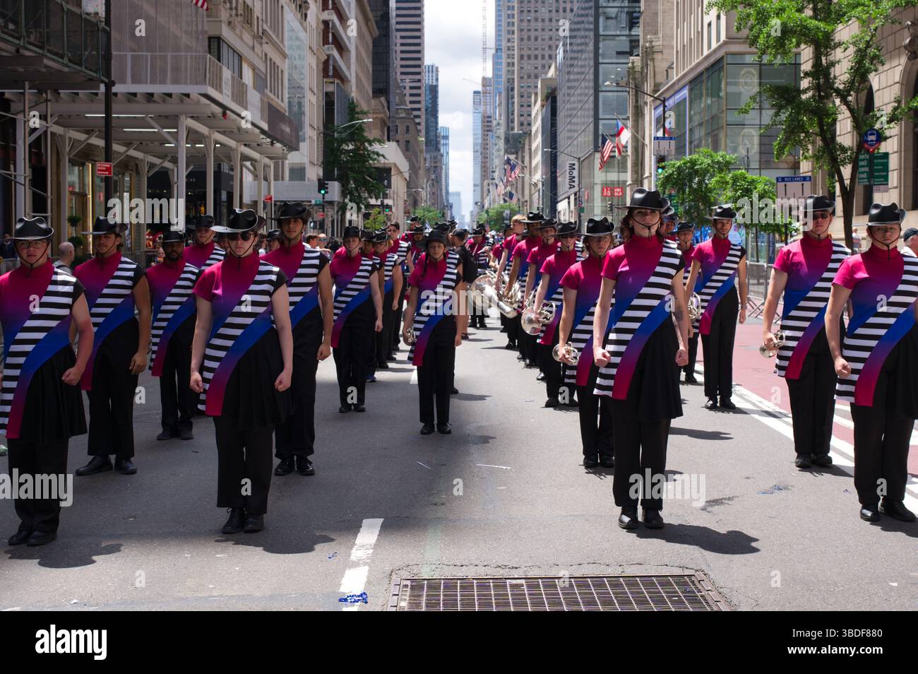 A large group of uniformed musicians, predominantly female, march down ...