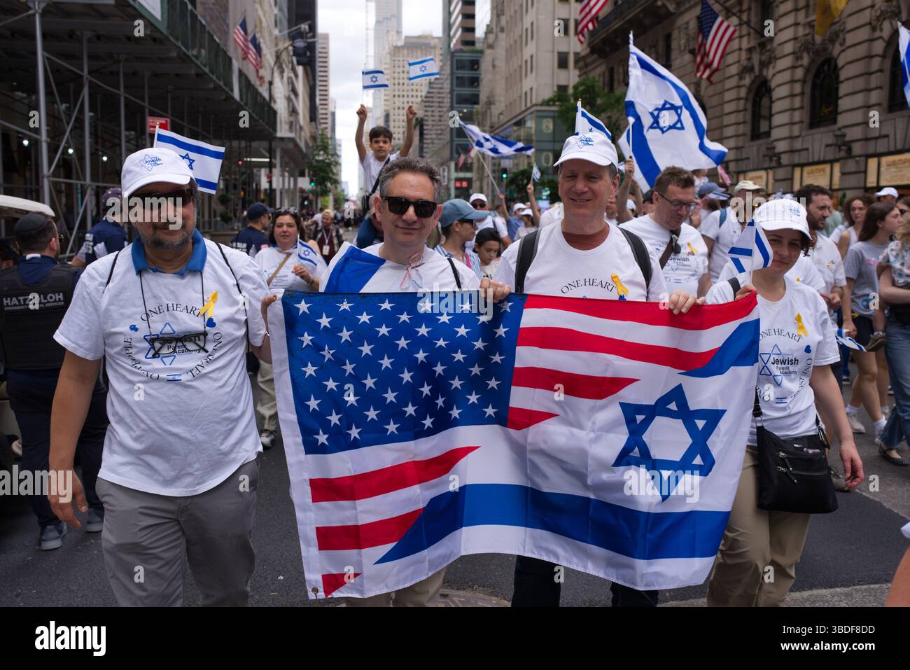 A group of people, predominantly wearing white "One Heart" shirts, hold ...