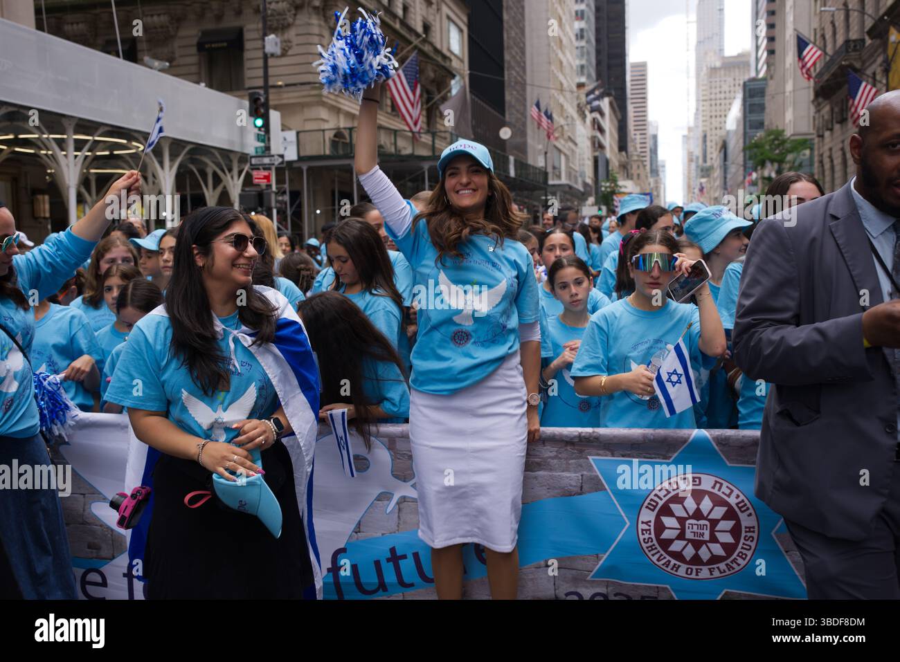 A large group of people, primarily women and girls, march in a street ...