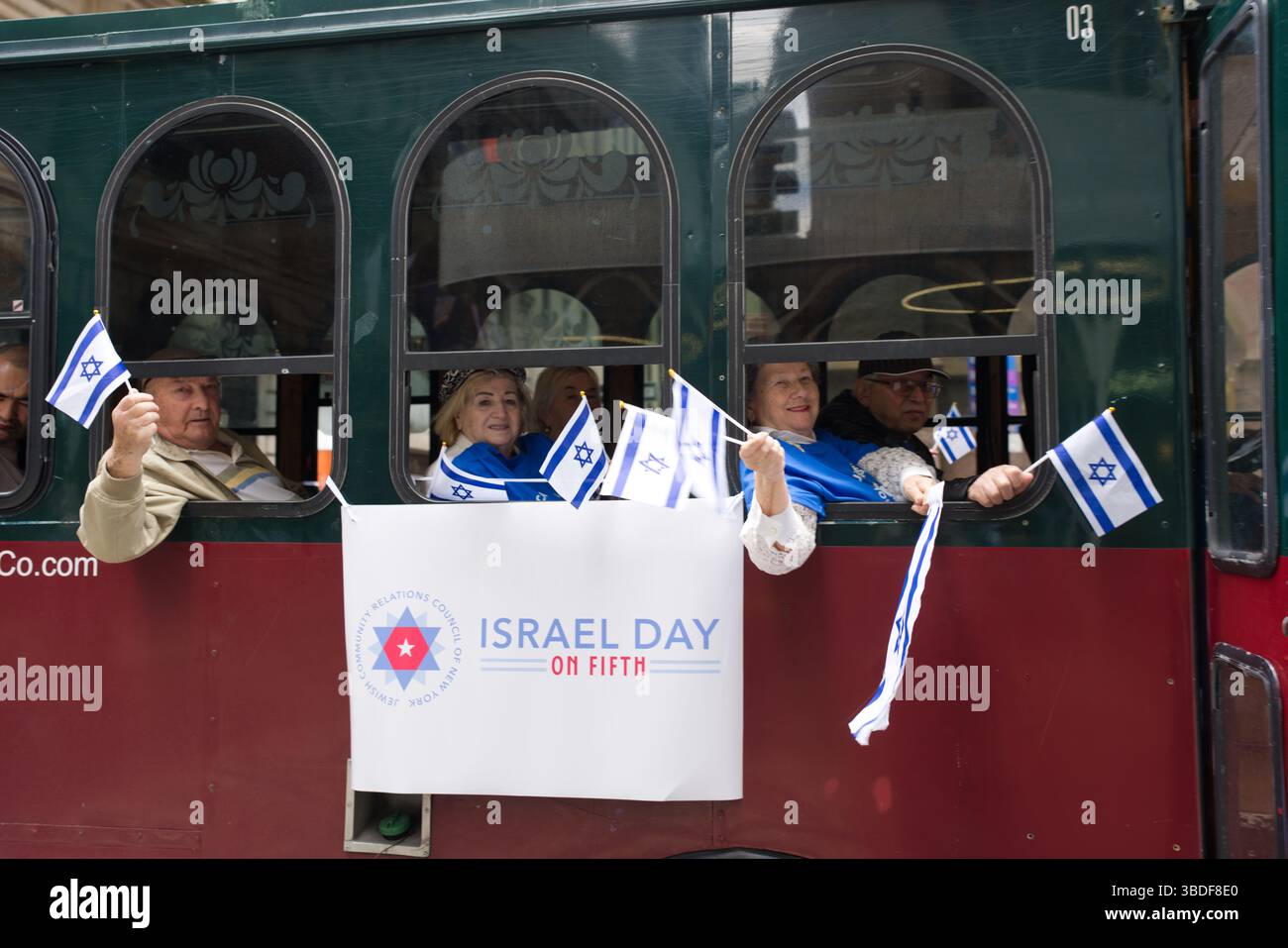 People inside a vintage green trolley hold Israeli flags during a ...