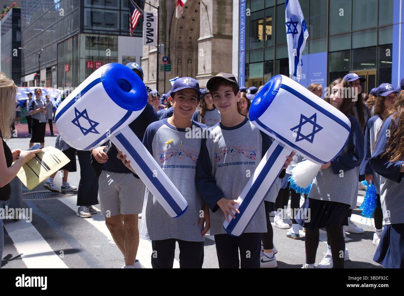 Two boys, smiling, hold large inflatable hammers decorated with the ...