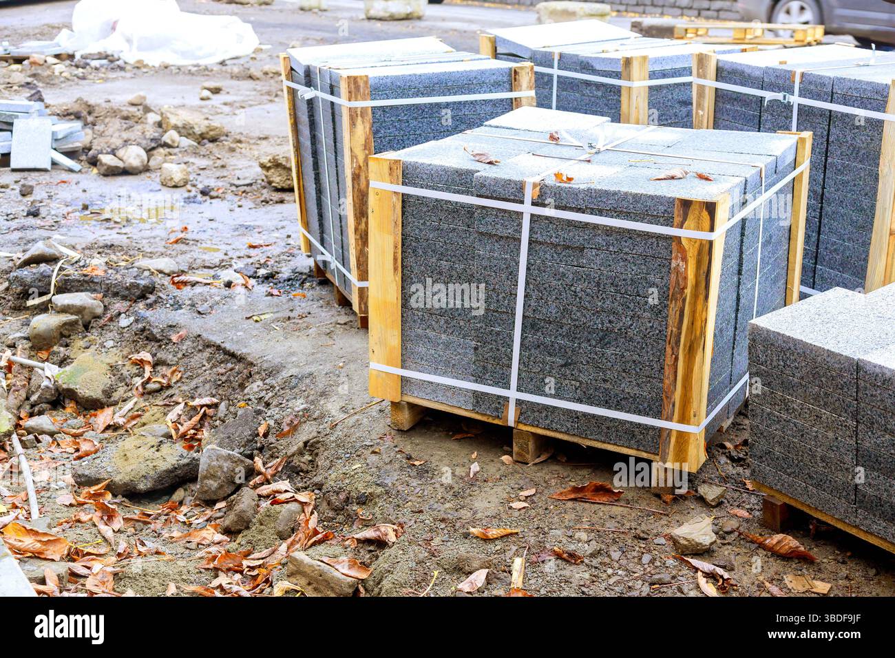 Multiple pallets of gray granite paving stones are stacked securely at ...