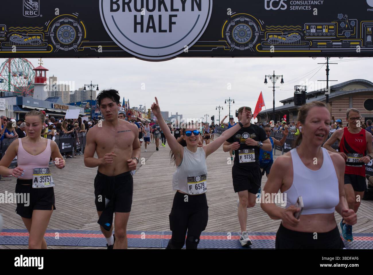 Runners cross the finish line of the Brooklyn Half Marathon, a road ...