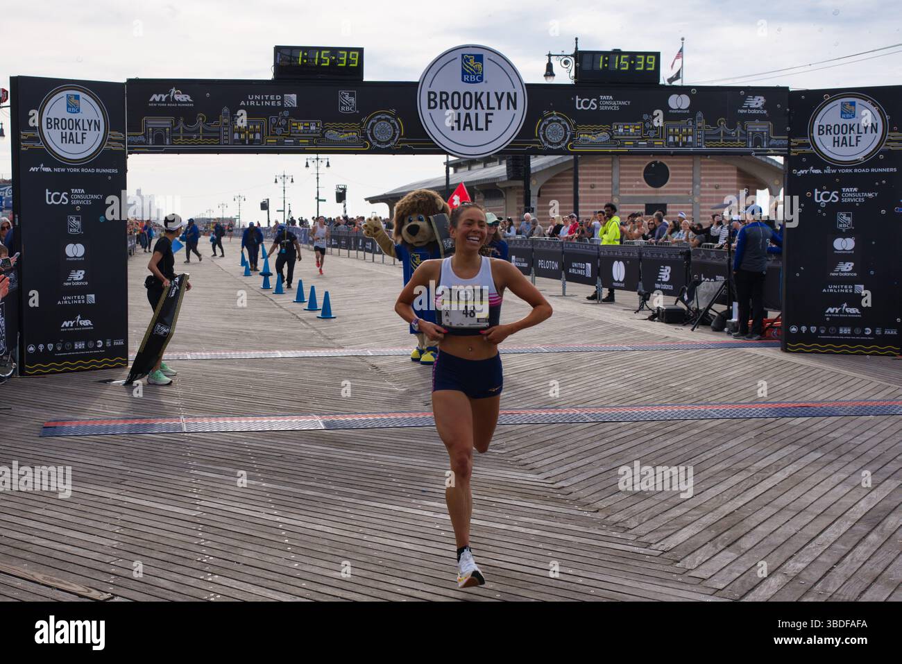 A female runner smiles while crossing the finish line of the Brooklyn ...