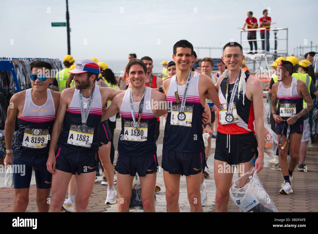 Five male runners, post-race, stand together smiling. They wear ...