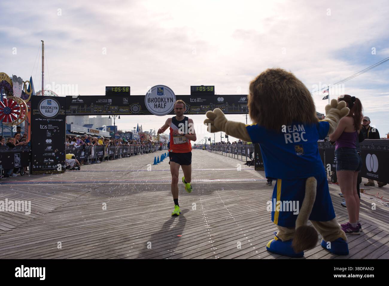 A male runner finishes a half marathon, crossing the finish line on a ...
