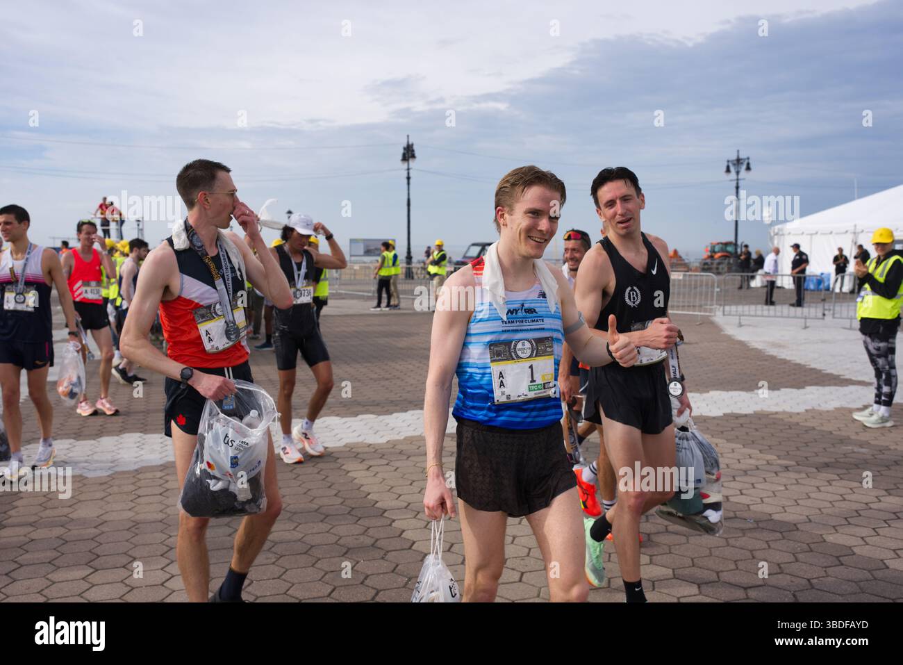 Post-race scene at a marathon featuring several male runners, some ...