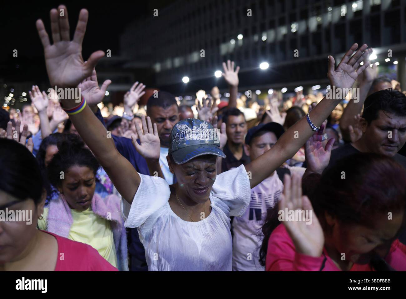 Evangelicals lift their hands in prayer during an outdoor service in a ...