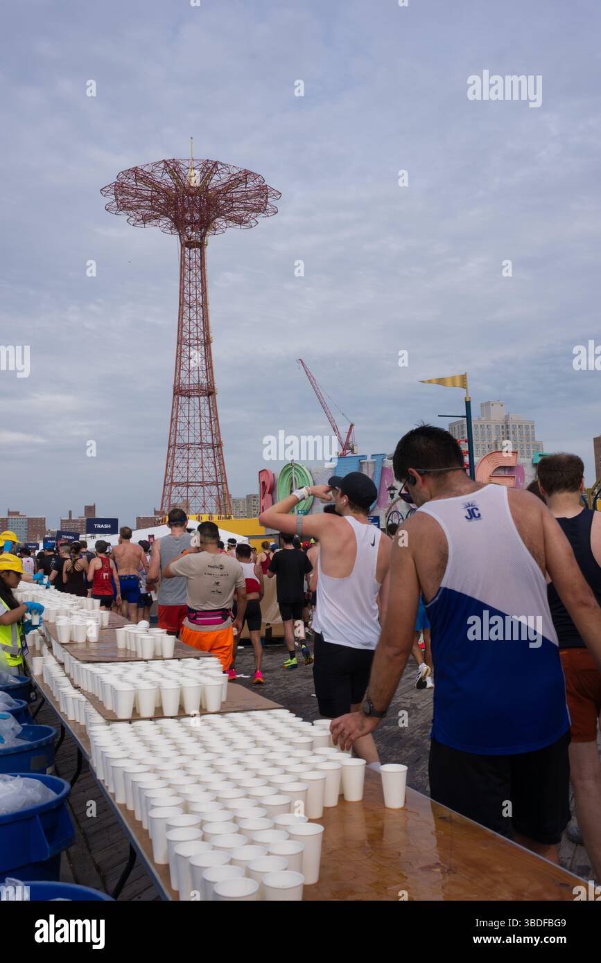 A long table laden with hundreds of white disposable cups sits outdoors ...