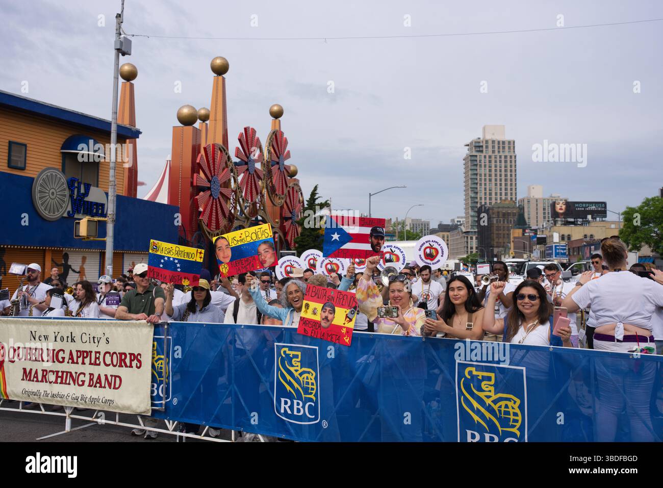 A vibrant crowd, primarily women, holds signs featuring portraits and ...