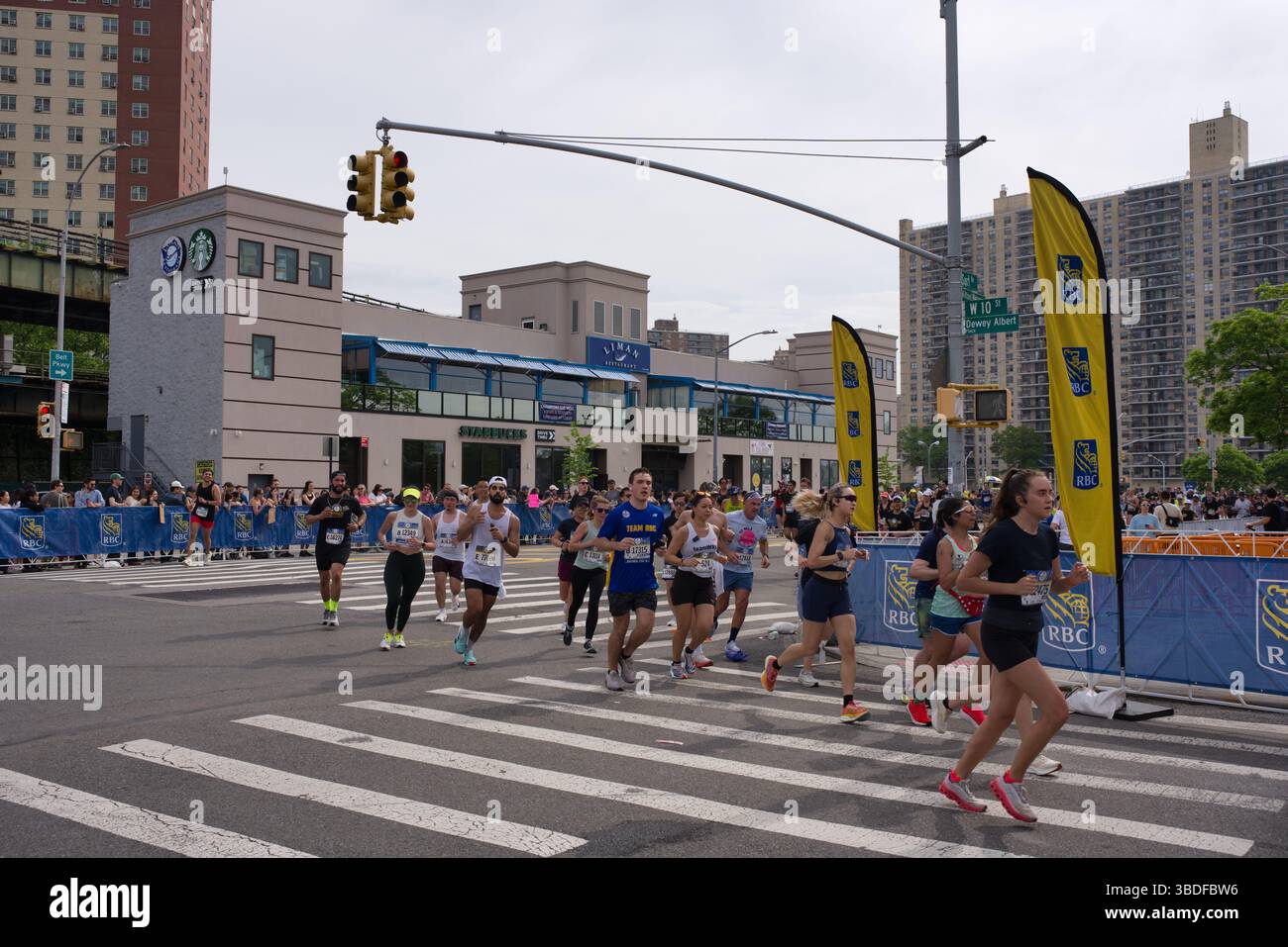 A street scene depicts numerous runners crossing a pedestrian crossing ...