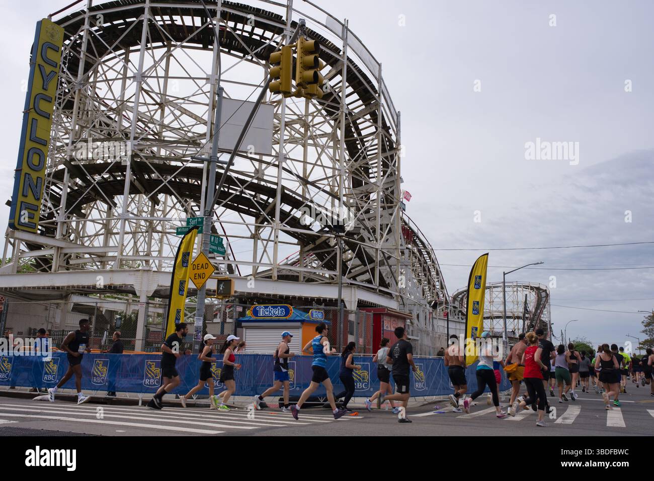 Runners participate in a road race with the Cyclone roller coaster in ...