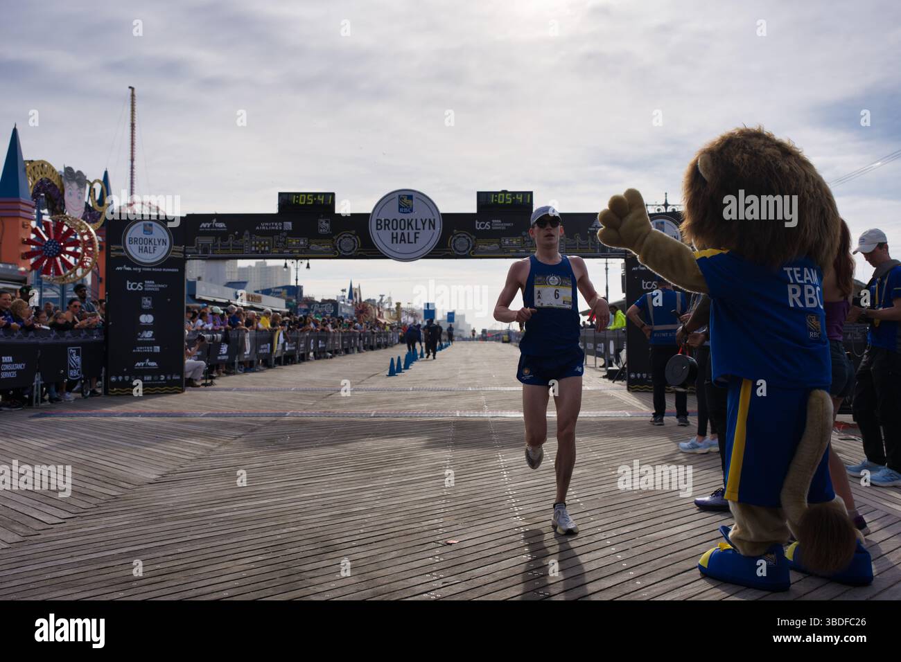A male runner nears the finish line of a half marathon on a boardwalk ...